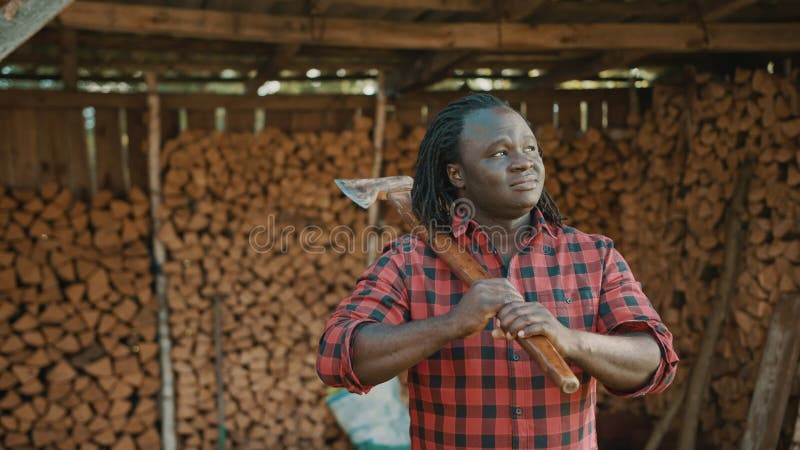 African Man with the Axe Standing in Front of Stack of Cutted Timber ...