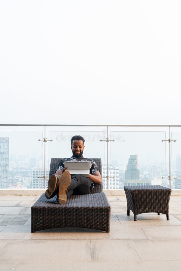 African Man Relaxing Outdoors while Using Laptop Computer and Mobile ...