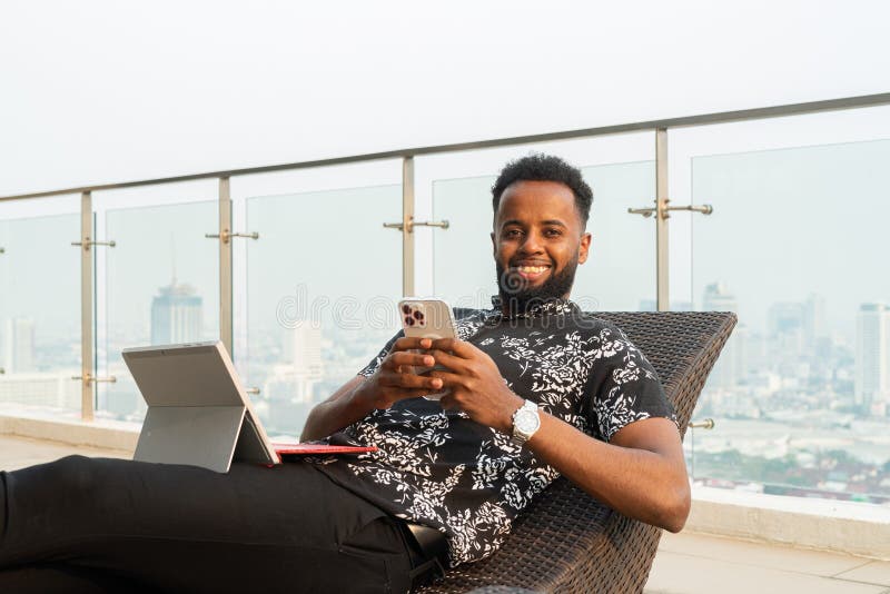 African Man Relaxing Outdoors while Using Laptop Computer and Mobile ...