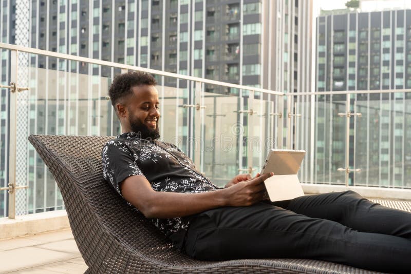 African Man Relaxing Outdoors while Using Laptop Computer and Mobile ...