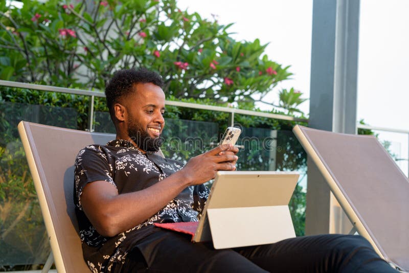 African Man Relaxing Outdoors while Using Laptop Computer and Mobile ...