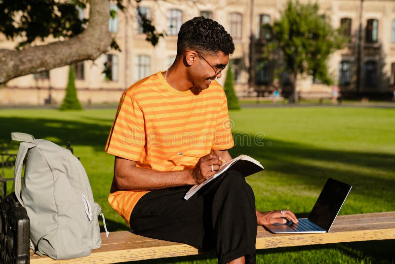 African Man Student Using Laptop and Writing Down Notes while Sitting ...