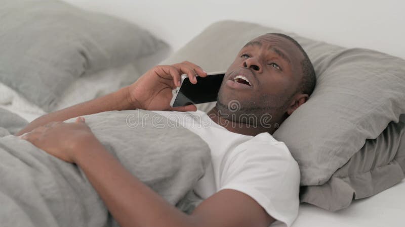 African Man Talking on Phone while Lying in Bed Stock Footage - Video ...