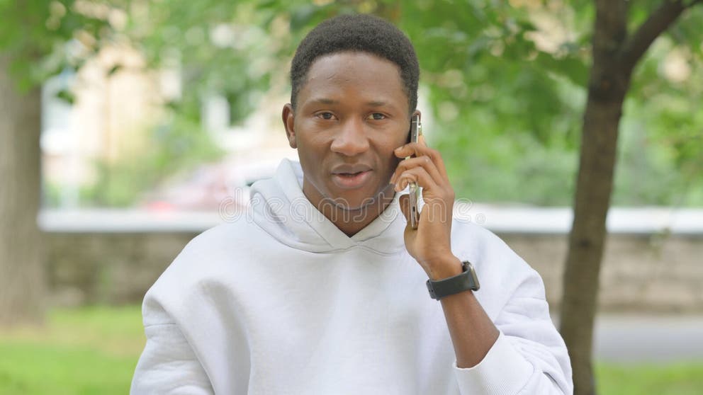 African Man Talking on a Smartphone in a Park Stock Photo - Image of ...