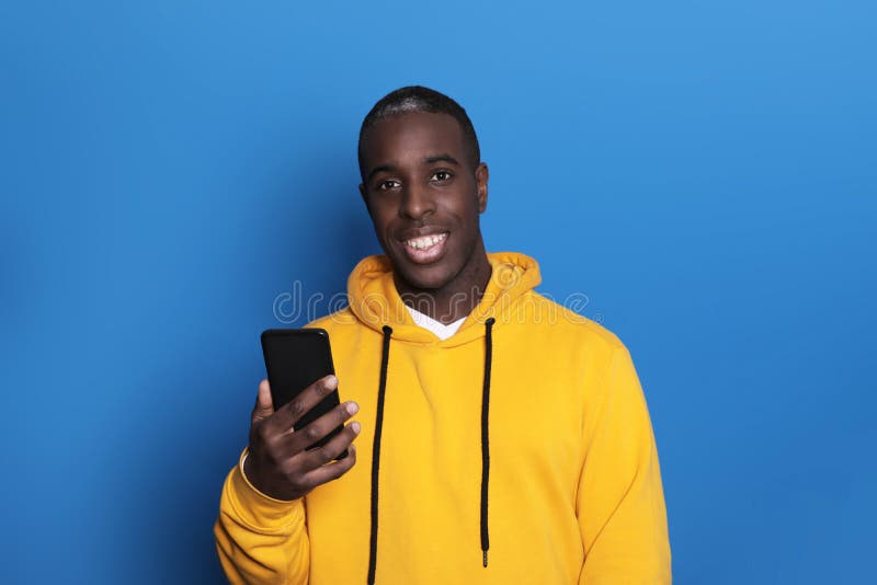 African Man Using Cellphone Texting and Looking Camera Posing Standing ...