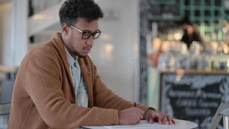 African Man Writing on Paper in Cafe Stock Photo - Image of data ...