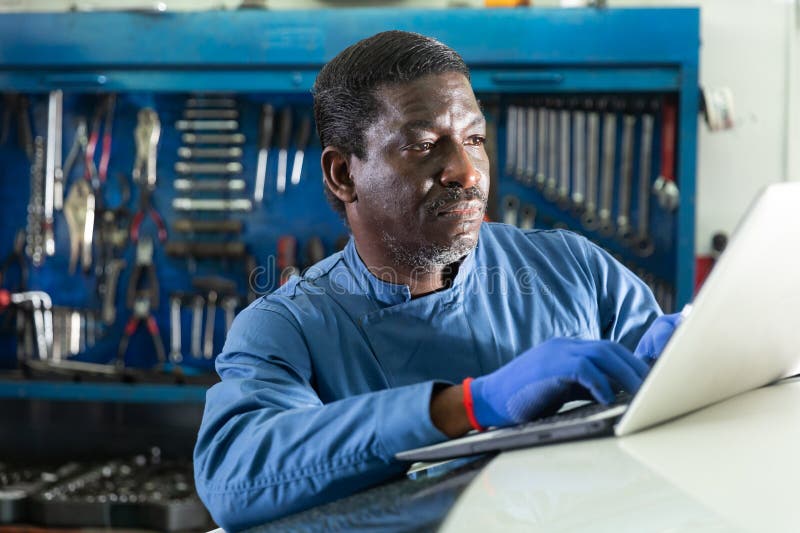 African Mechanic Man Using a Laptop Computer Checking Car in Workshop ...