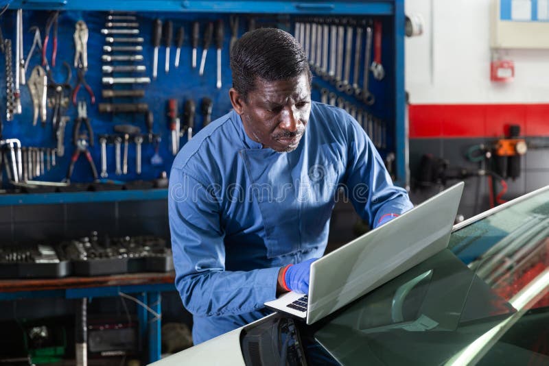 African Mechanic Man Using a Laptop Computer Checking Car in Workshop ...