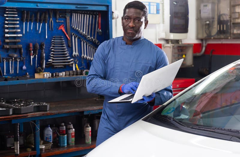 African Mechanic Man Using a Laptop Computer Checking Car in Workshop ...