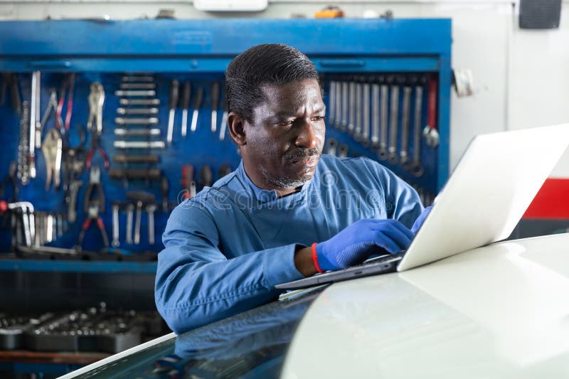 African Mechanic Man Using a Laptop Computer Checking Car in Workshop ...