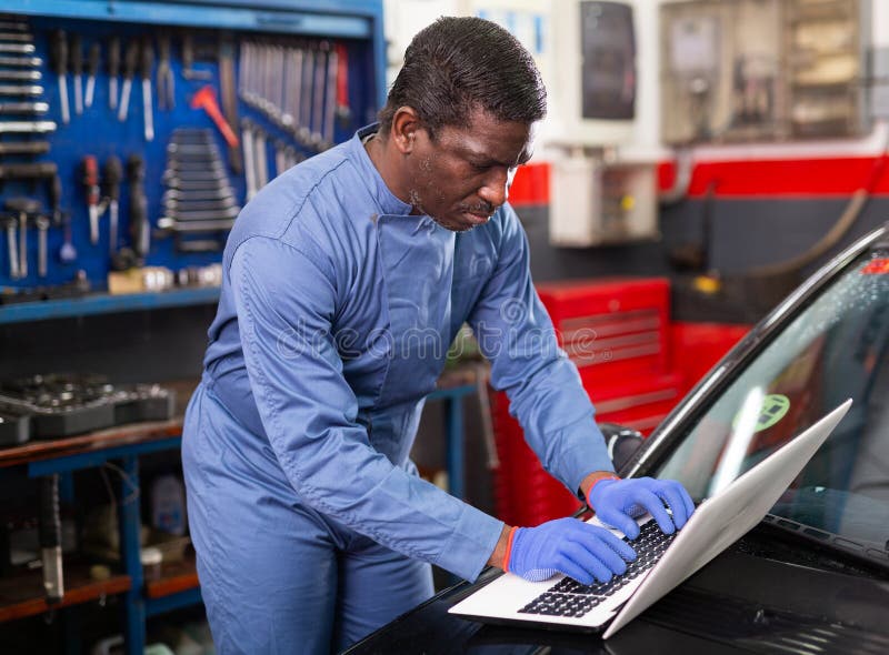 African Mechanic Man Using a Laptop Computer Checking Car in Workshop ...