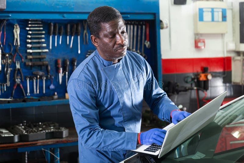 African Mechanic Man Using a Laptop Computer Checking Car in Workshop ...