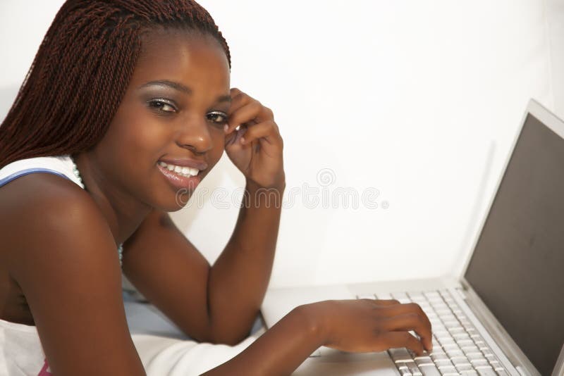 African Teen Working on Laptop Computer and Talking on a Cell Ph Stock ...