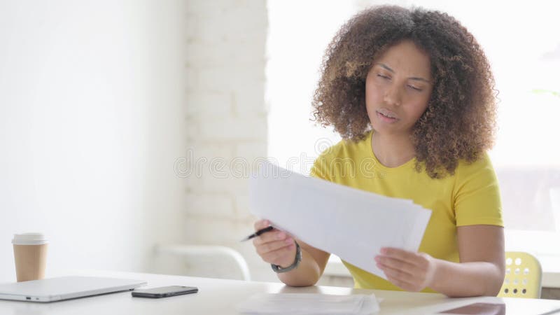African Woman Reading Documents while Sitting in Office Stock Photo ...