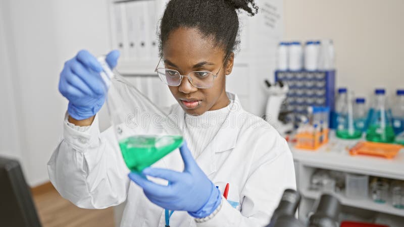 African Woman Scientist Analyzing a Green Solution in a Laboratory ...