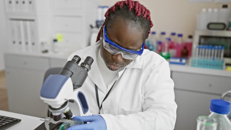 African Woman Scientist Analyzing Samples with Microscope in Biomedical ...