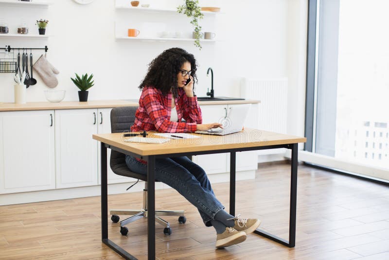 African Woman Working Remotely on Laptop in Modern Home Kitchen Setting ...