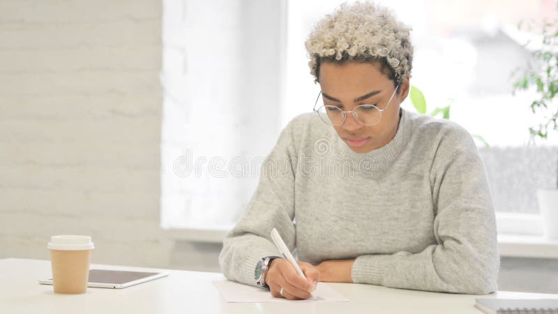 African Woman Thinking while Writing on Paper in Office Stock Image ...