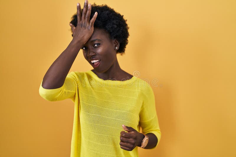 African Young Woman Standing Over Yellow Studio Surprised with Hand on ...