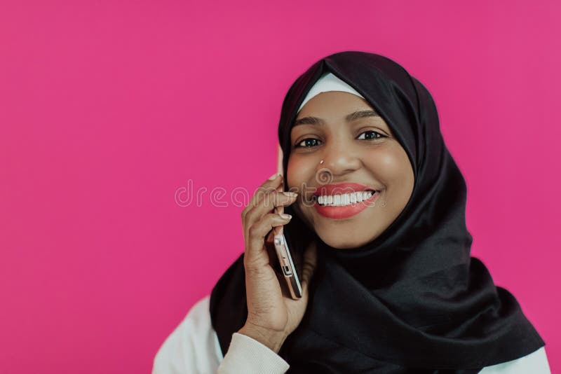Afro Woman Uses a Smartphone in Front of a Pink Background Stock Image ...