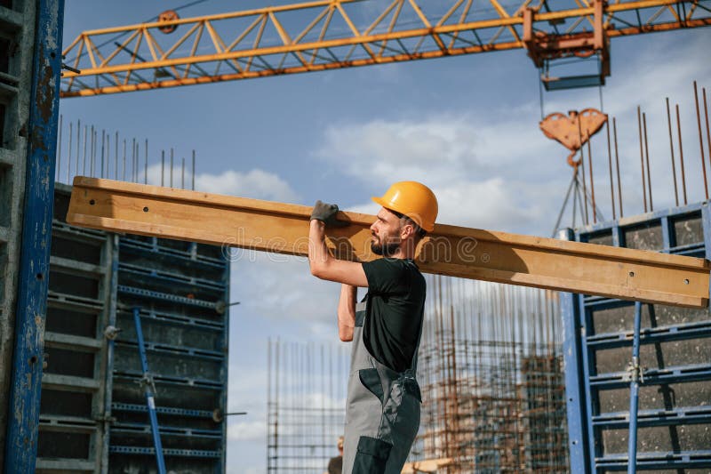 Against Crane with Wooden Plank. Man in Uniform is Working on the ...