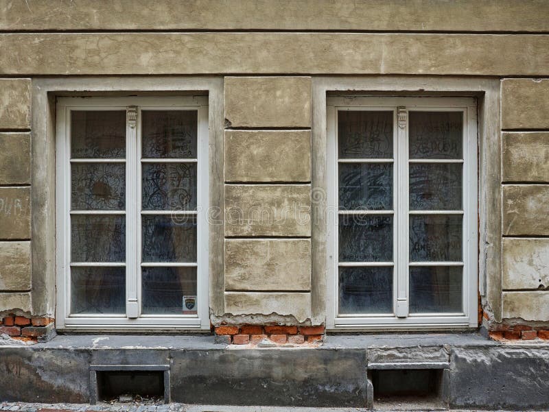 Aged Building with Two Windows on a Weathered Wall, Revealing Bricks ...