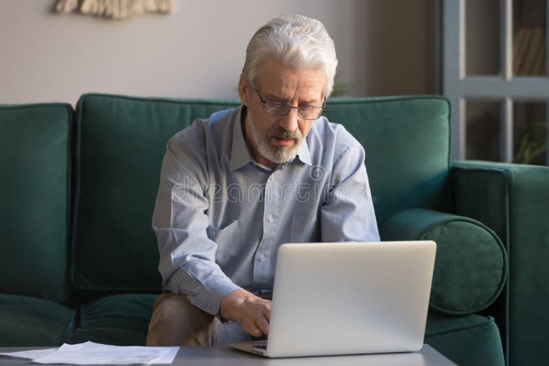 Aged Man Sitting on Couch Working on Laptop at Home Stock Image - Image ...