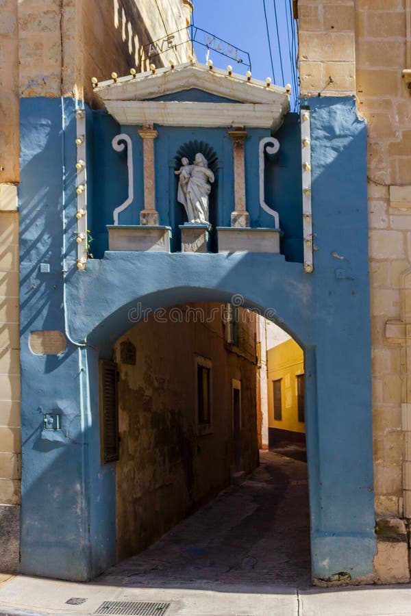 Historic Archway with Decorative Statue Along a Narrow Alley in Sunny ...