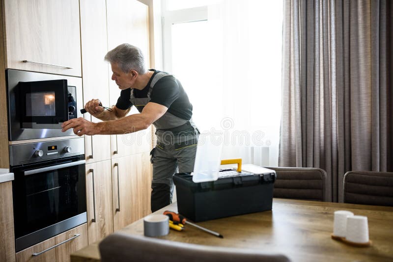 Make Your Life Easier. Aged Repairman in Uniform Working, Fixing Broken ...