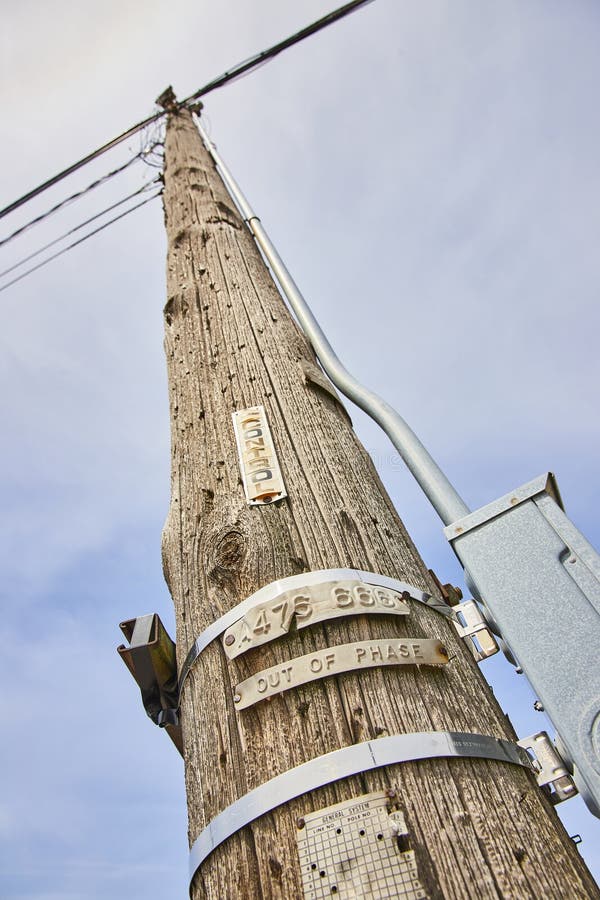 Aged Utility Pole with Warning Tags and Conduits, Low-Angle View Stock ...