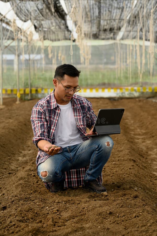 Agronomist Using Digital Tablet and Assessing Soil Conditions in a ...