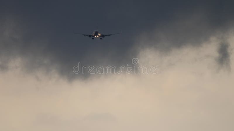 Airplane Approaching for Landing through Overcast Skies at Sunset Stock ...