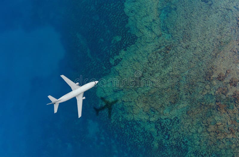 Airplane Flying Over Clear Blue Ocean with Reef Visible Below Stock ...
