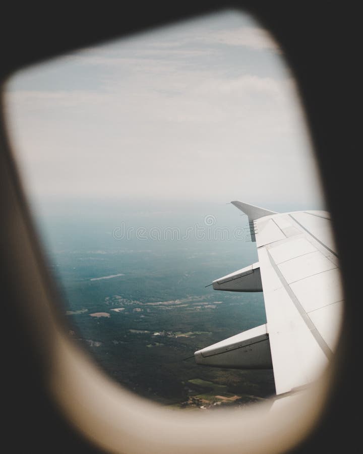 Airplane`s Window with the View of the Green Fields Above and the Right ...