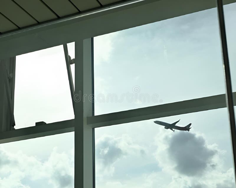 An Airplane Flying in the Sky Out a Window at an Airport Stock Photo ...