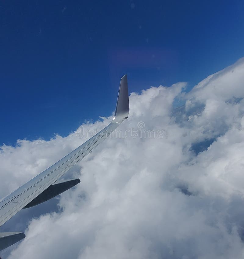 Airplane Wing in White Fluffly Clouds with Blue Sky Background Stock ...