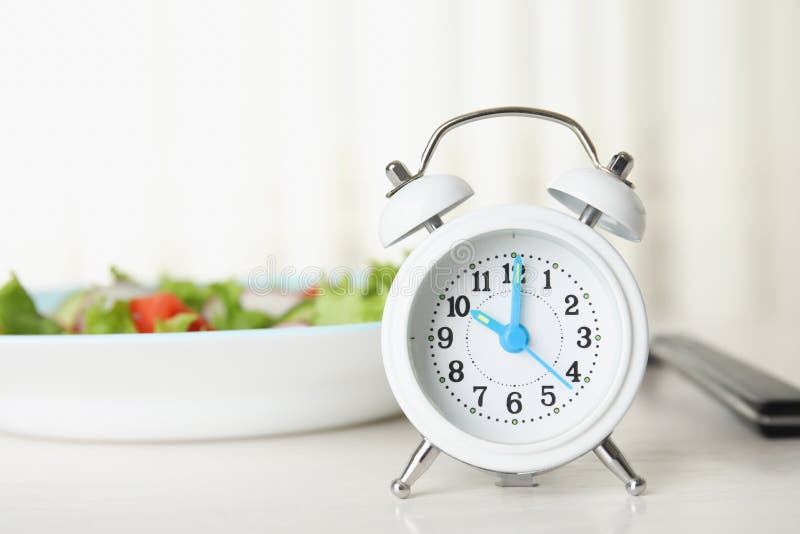Alarm Clock and Plate with Salad on White Table. Meal Timing Concept ...