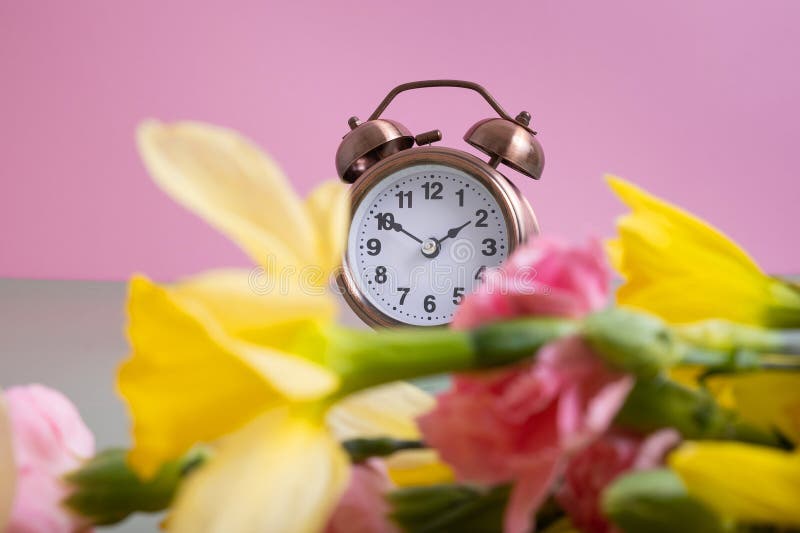 Alarm Clock with Spring Flowers. Spring Time, Daylight Savings Concept ...