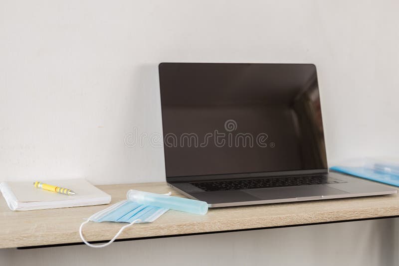 Alcohol Spray Bottle and Surgical Mask on Table with Laptop Computer at ...