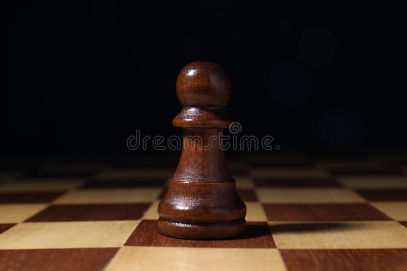 Black Pawn in Front of White Pieces on Wooden Board Against Dark ...