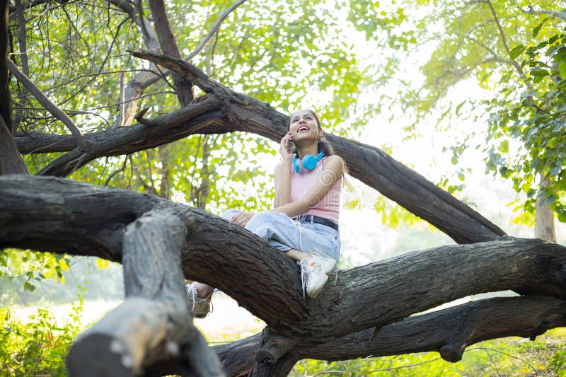 Alone Woman Talking on Phone while Sitting on Tree Branch Stock Image ...