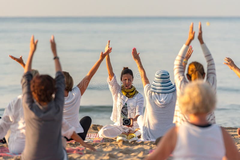Yoga Instructor Leading a Group Session at Sunset on the Beach in ...