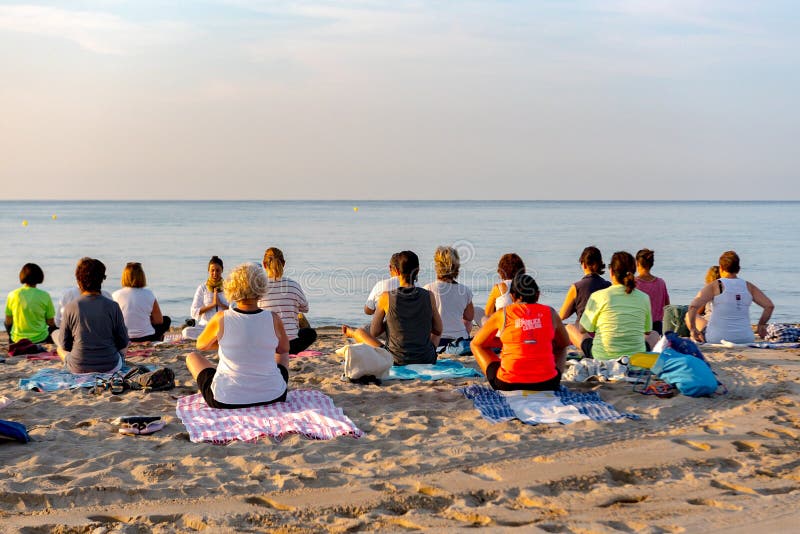 Yoga Instructor Leading a Group Session at Sunset on the Beach in ...