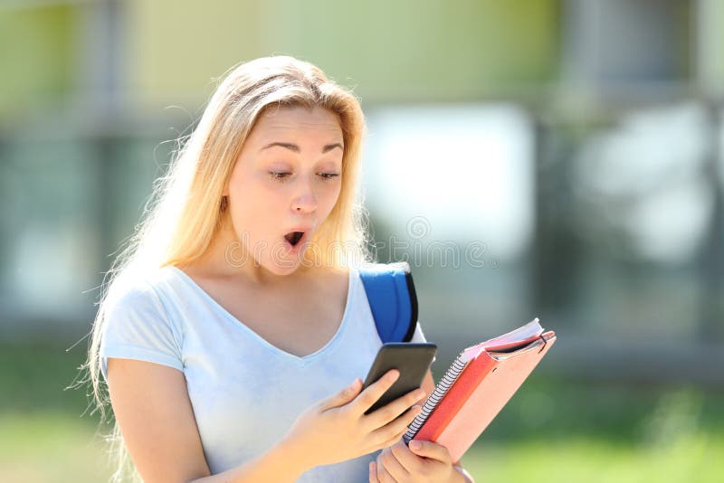 Amazed Student Checking Phone Content in a Campus Stock Photo - Image ...