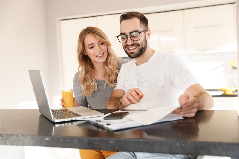 Amazing Happy Young Loving Couple Sitting at the Kitchen Using Laptop ...