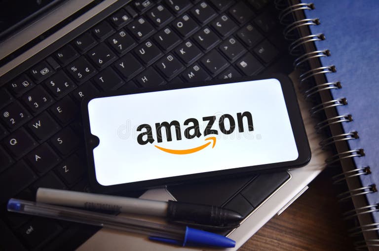 Amazon Logo Seen on a Mobile Phone Screen on a Table with Objects in ...