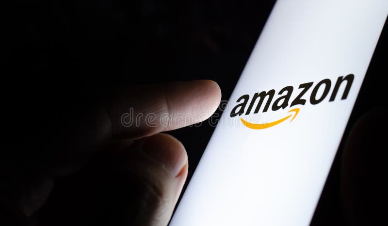 Amazon Logo on a Smartphone Screen in a Dark Room and a Finger Pointing ...