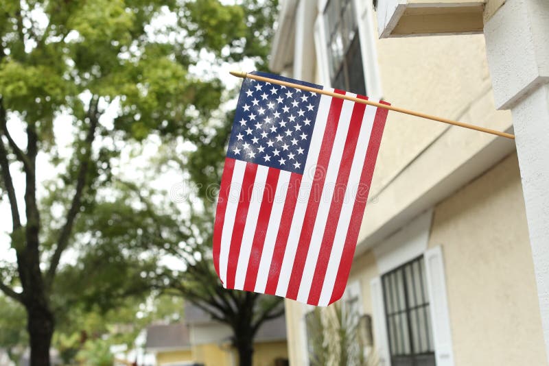 American Flag on a Stick in Front of a House Stock Photo - Image of ...