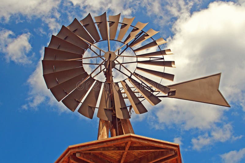 American Windmill into the Water Against a Blue Sky with White Clouds ...