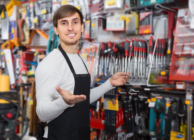 Amiable Young Salesman in Apron with Tools Stock Photo - Image of ...